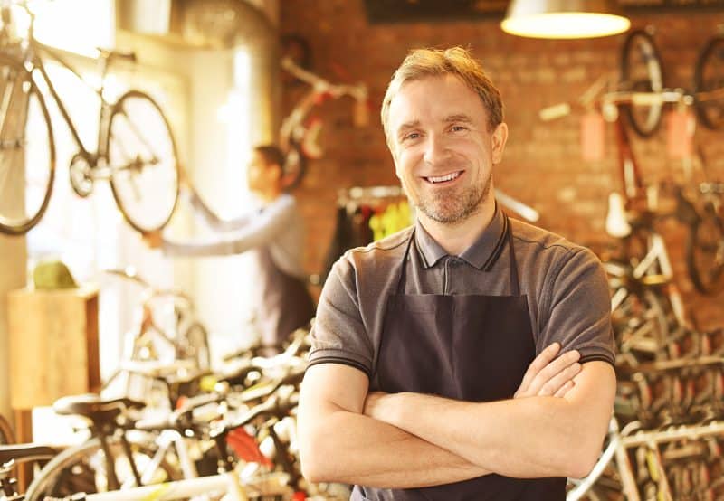bike shop owner stands proudly in front of his stock | Knight-Dik Insurance